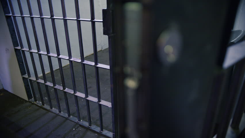 A Static Camera Closeup Of The Door Slamming Shut A Brick Jail Cell With Iron Bars Stock Footage
