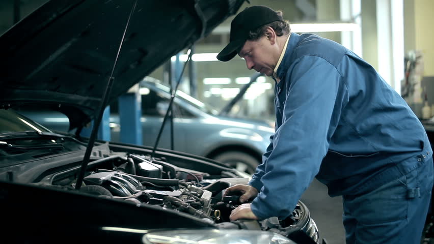 Male Tutor Instructing Female College Student In Car Mechanics Class As ...