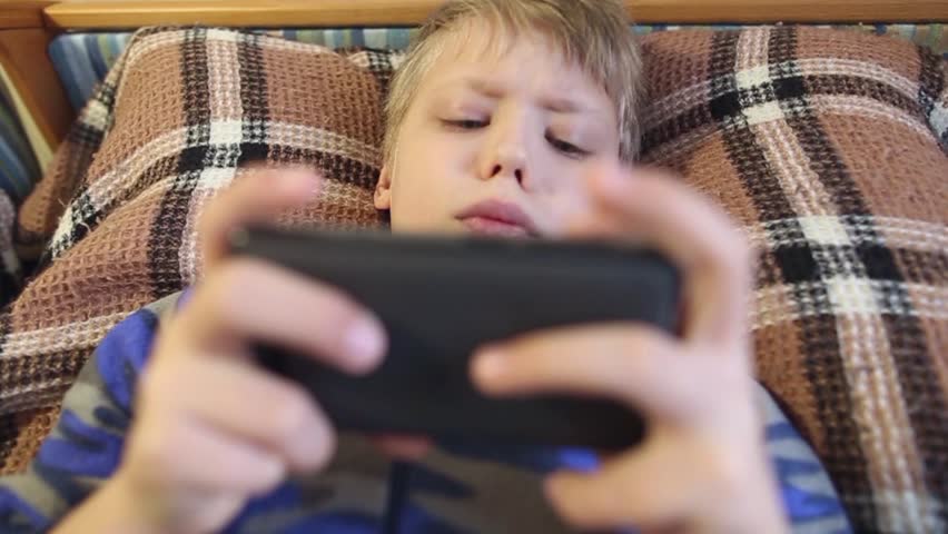 8 Years Old Kid Playing Computer Games While Laying In His Bed In ...