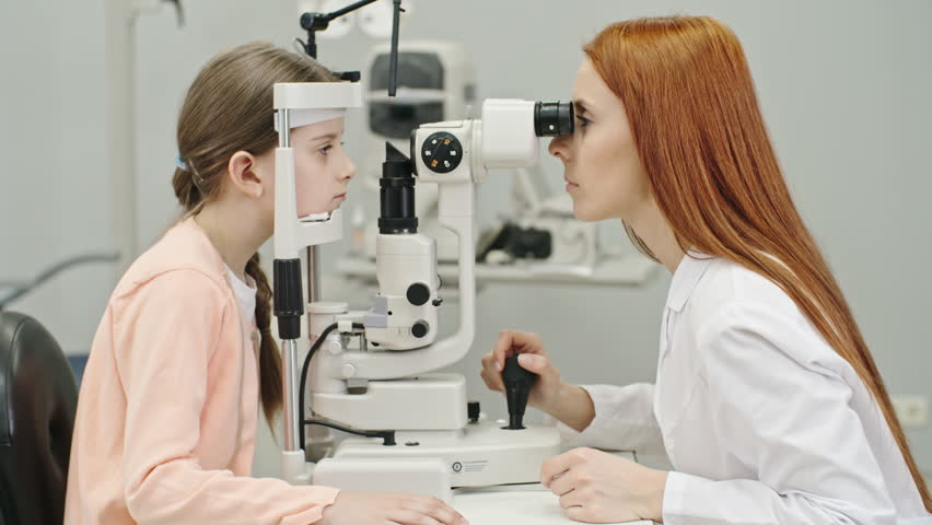 Female Pediatric Optometrist Examining Eyes Of Little Girl With ...