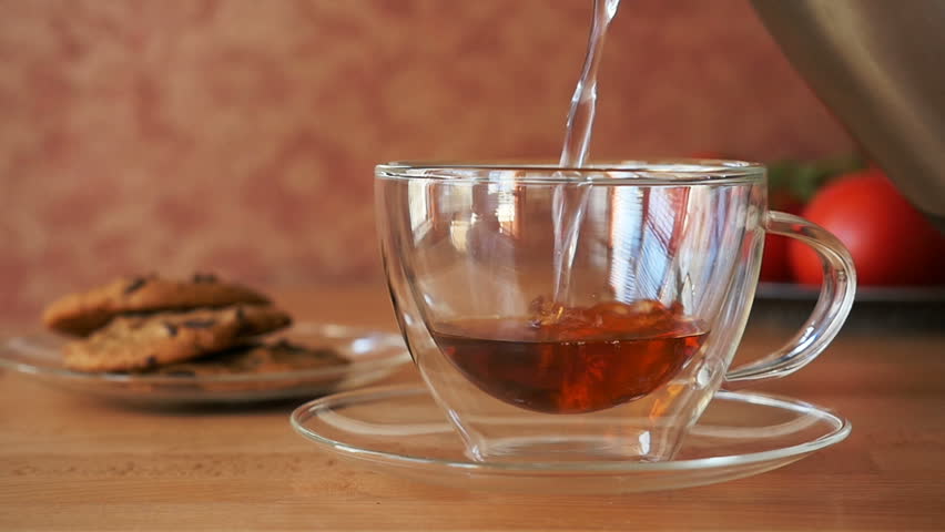 Tea Pouring Into Cup Slow Motion. A Transparent Cup On A Plate Being ...