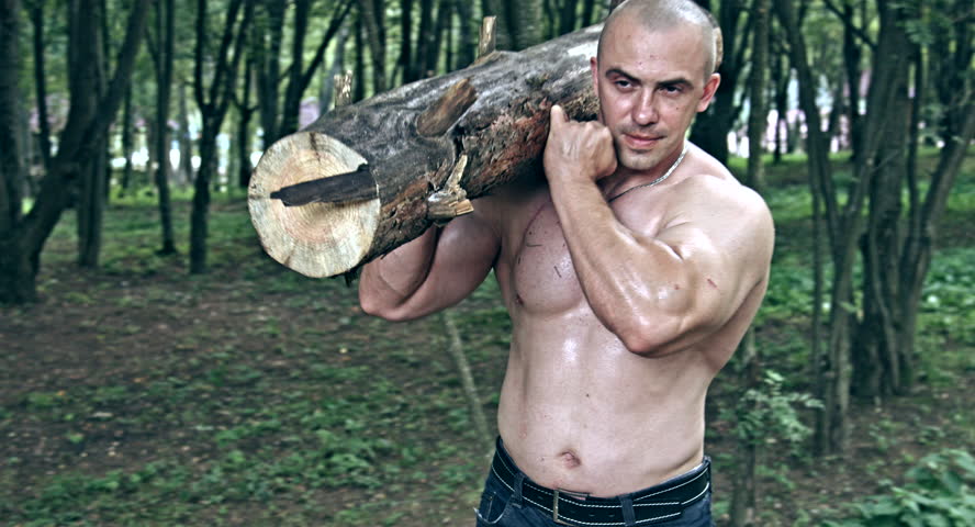 Strong Muscular Man Carries A Huge Felled Tree In The Forest. Stock ...