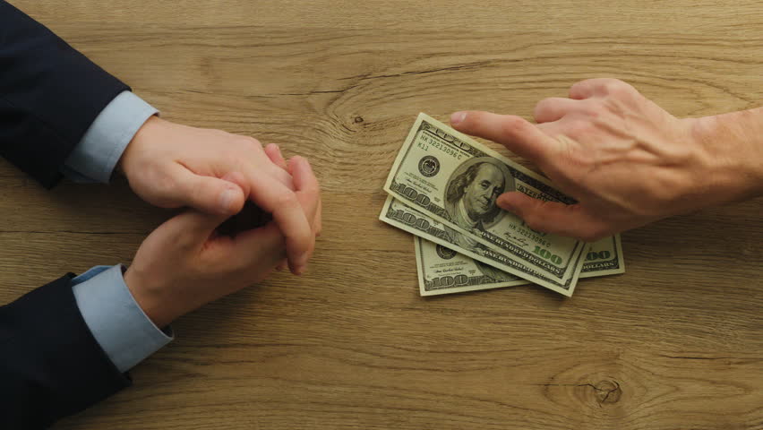 A Man Counts Out Hundred Dollar Bills Into The Hand Of Another ...