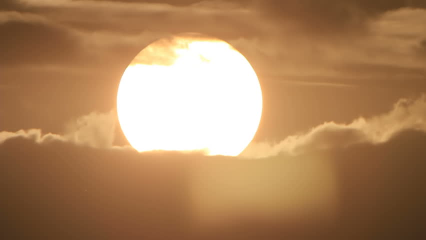 The Sun Slowly Sets Through The Clouds In A Huge Orange Ball. Stock ...