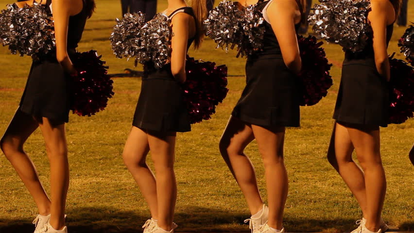 High School Cheerleaders Stand On Sidelines, Pompoms In Hand, Watch ...