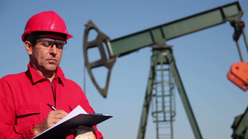 Refinery Worker And Pipelines. Worker Wearing Red Overalls And Hardhat ...