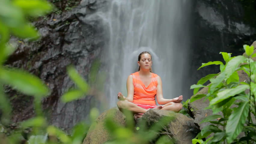 Woman Sitting In Meditation Under Waterfall In Bali, Indonesia Stock ...