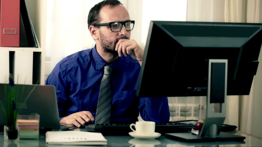 Young, Handsome Man Sitting Behind The Desk And In Using Computer, Then ...