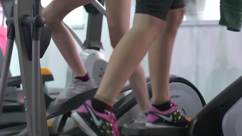 The Girl On A Bicycle In A Gym. Beautiful Girl In Red T-shirt Pedals In ...