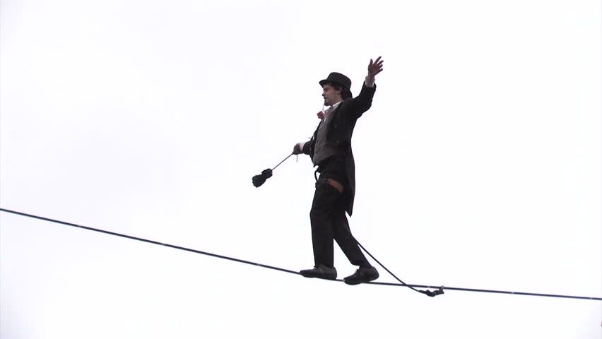 Trapeze Artist Performing Balancing Act On A High Wire To A Crowd In ...